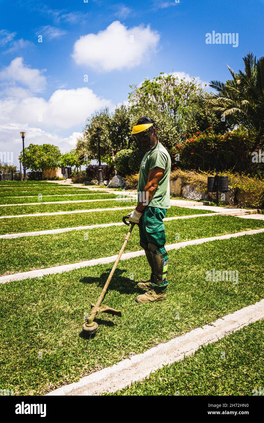 Worker in a special uniform doing lawn mowing in the yard Stock Photo ...