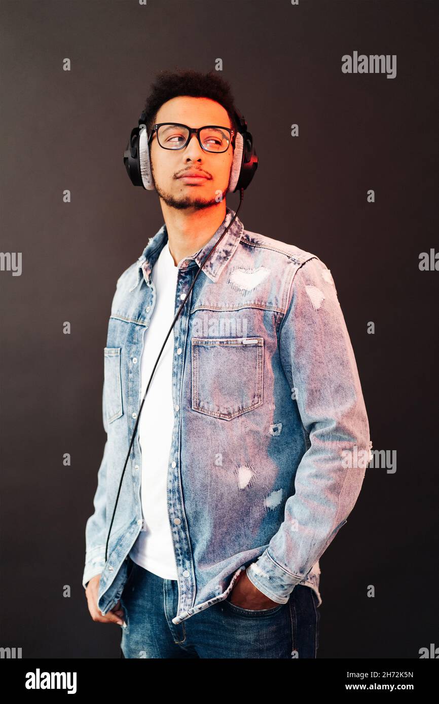 Young African American man wearing headphone and enjoy music over black ...