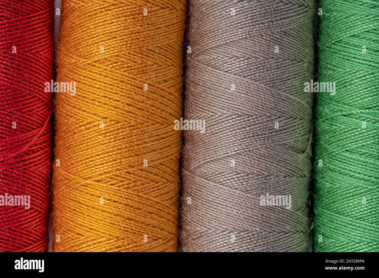Four bobbins of sewing thread of red green orange and brown color Stock ...