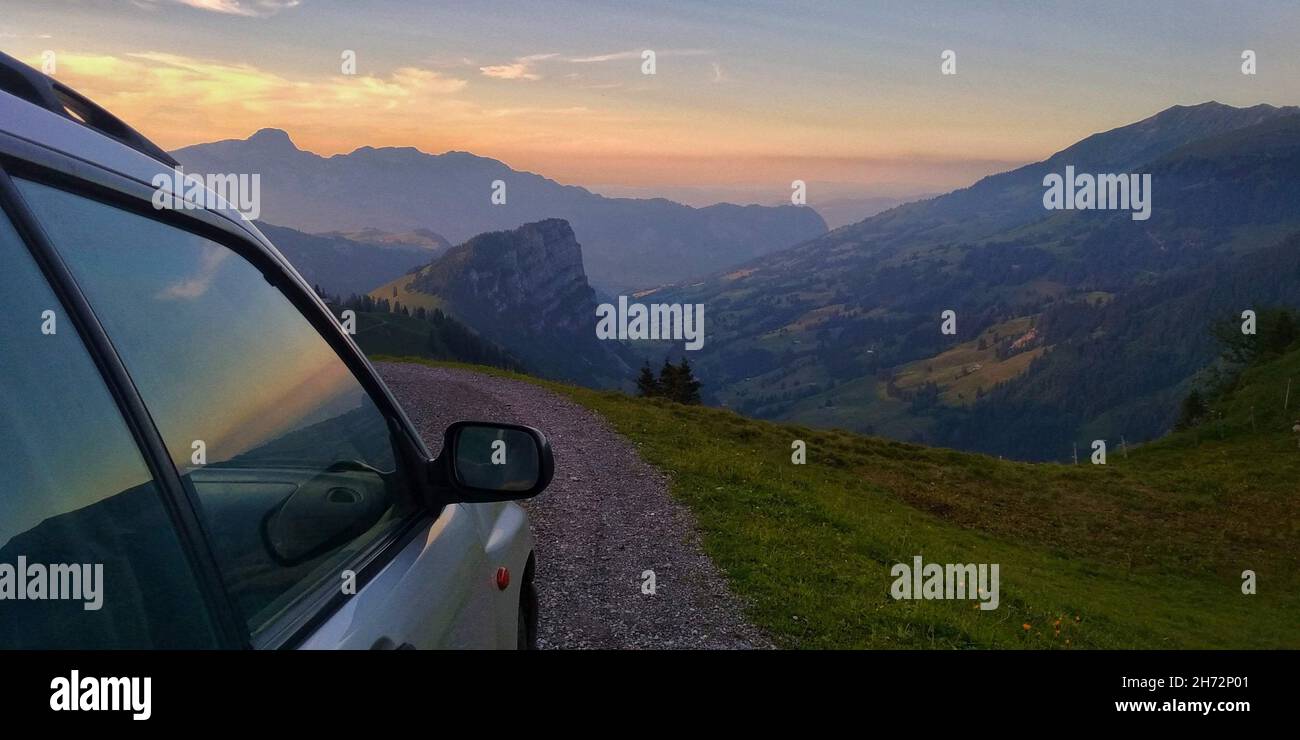 Car driving on a road in the mountains with scenic sunset background ...