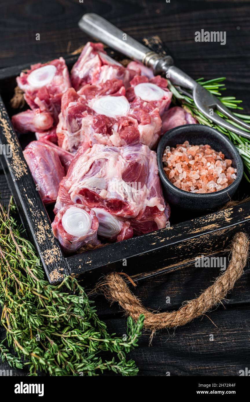 Raw veal beef Oxtail Meat in wooden tray with thyme. Black wooden ...