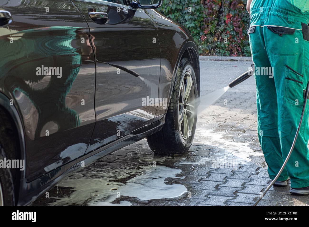 Man washing her car in car wash .A man washes a car in a manual car ...