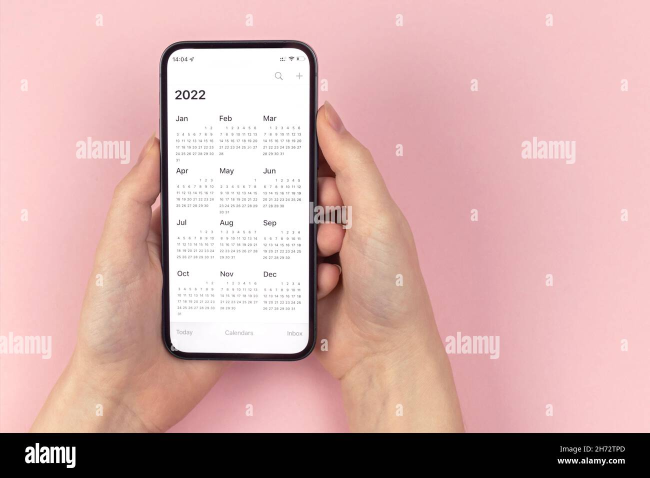 Calendar 2022. Smartphone in woman hands. Pink background, workspace ...