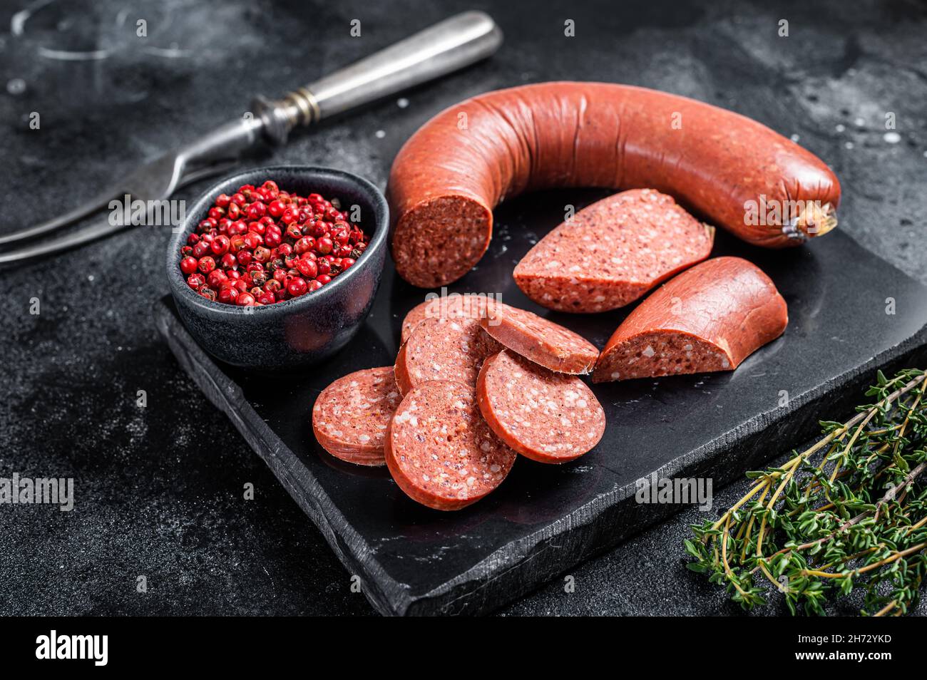 Turkish Sliced Sucuk meat sausage on a marble board with thyme. Black ...