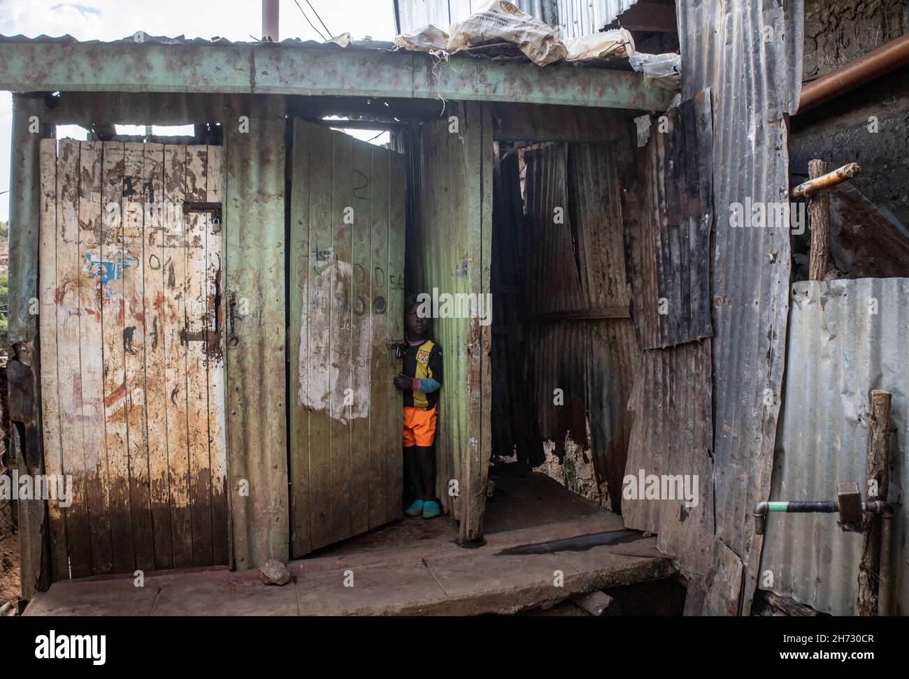 A young boy stands outside the doors of a local latrine in Kibera Slums ...