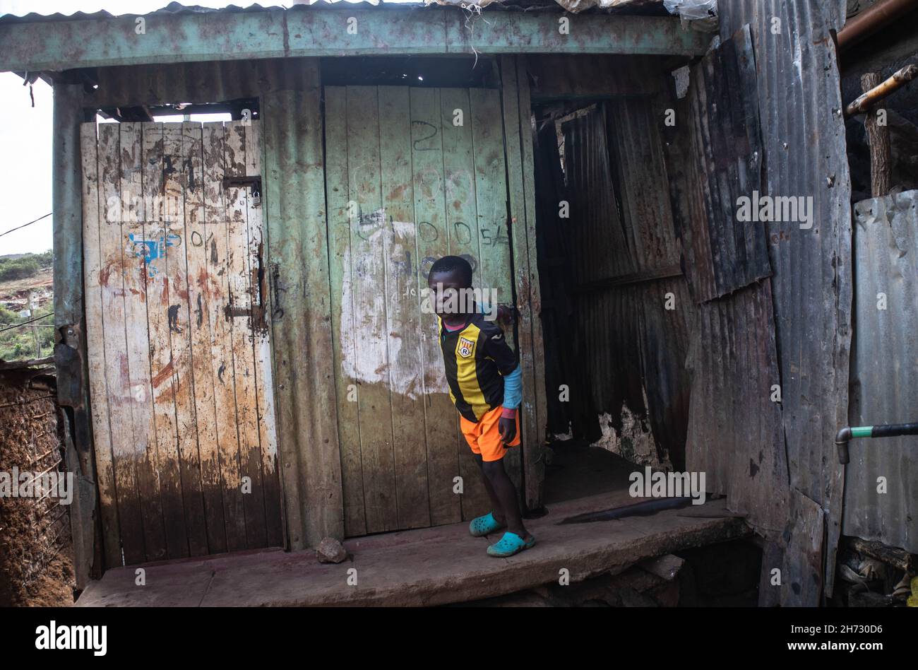A young boy walks outside the doors of a local latrine in Kibera Slums ...