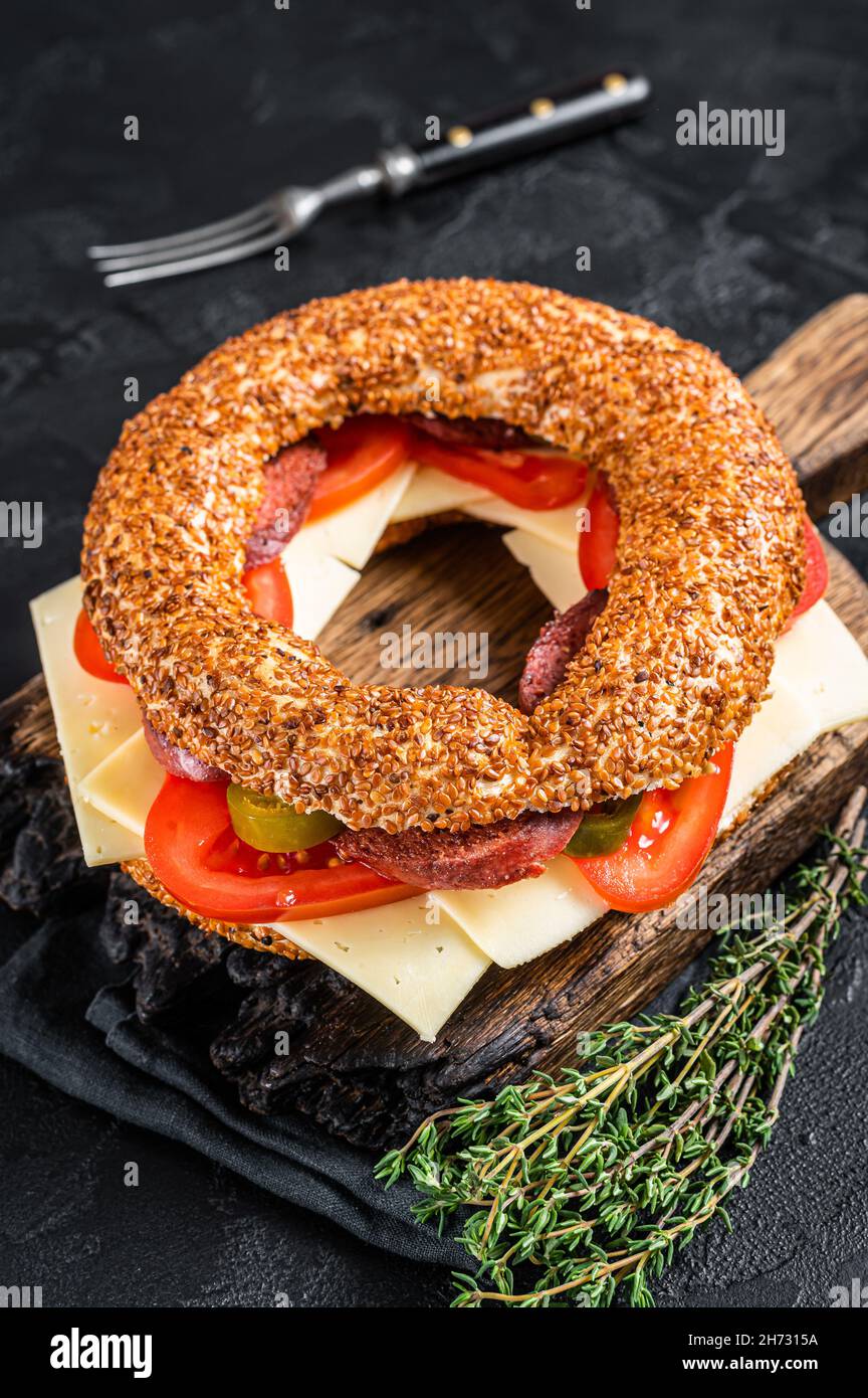 Simit bagel sandwich with lettuce, tomato, yellow cheese and ham. Black ...