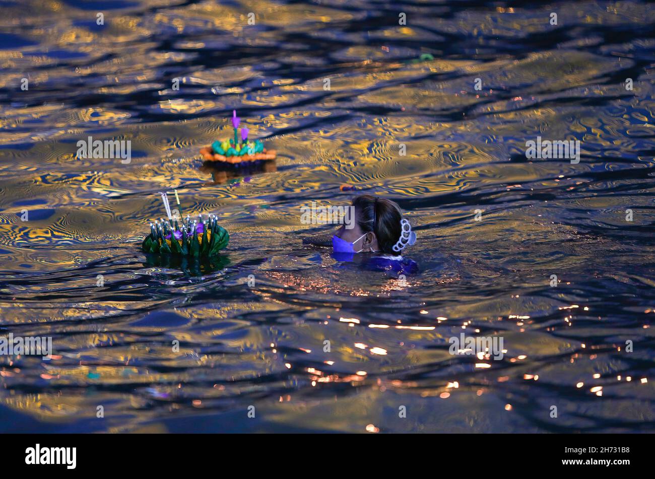 A woman carries a krathong into the Chao Phraya river during the Loy Krathong festival ...