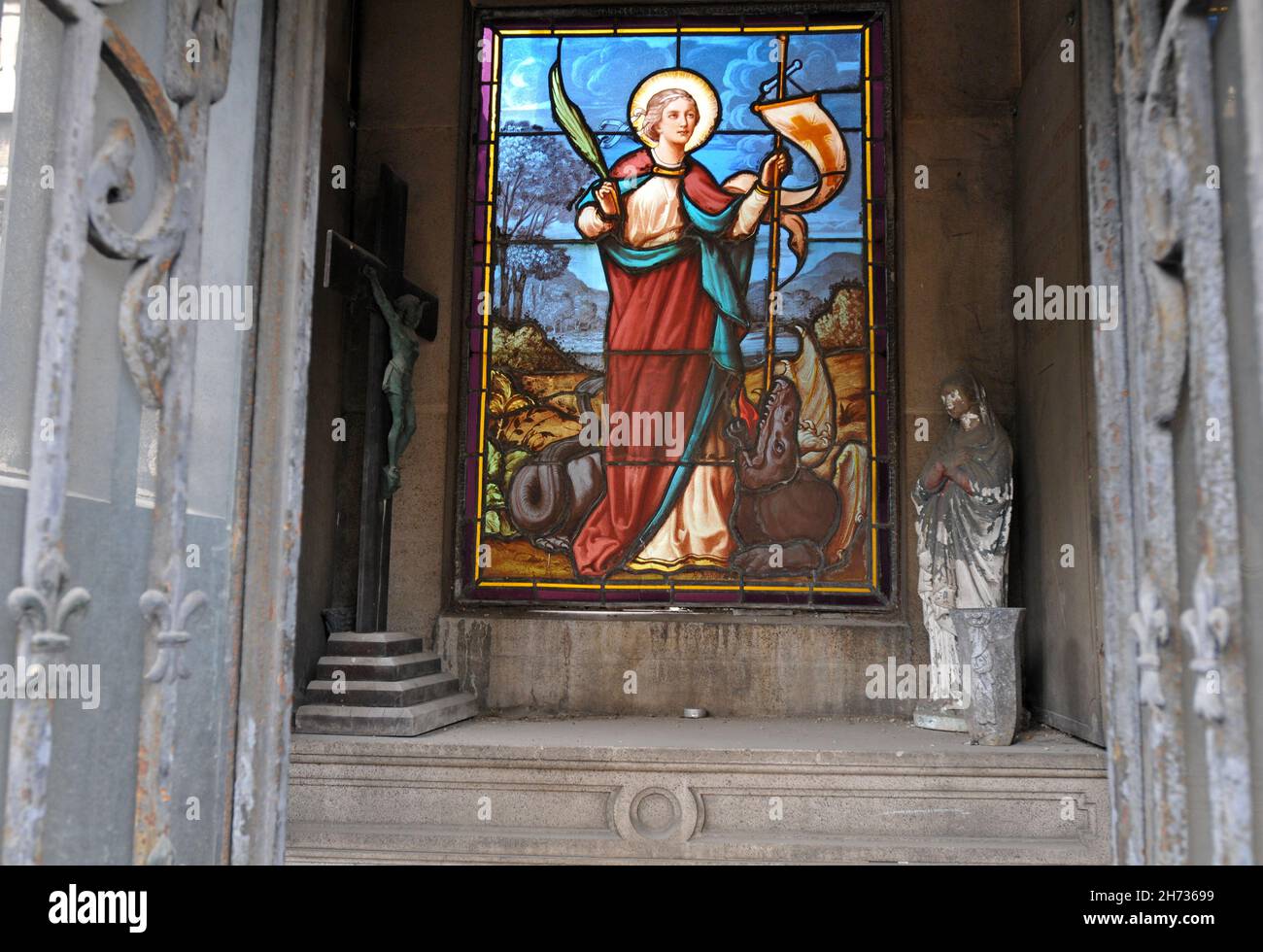 A stained glass window and dust-covered religious statues are pictured ...
