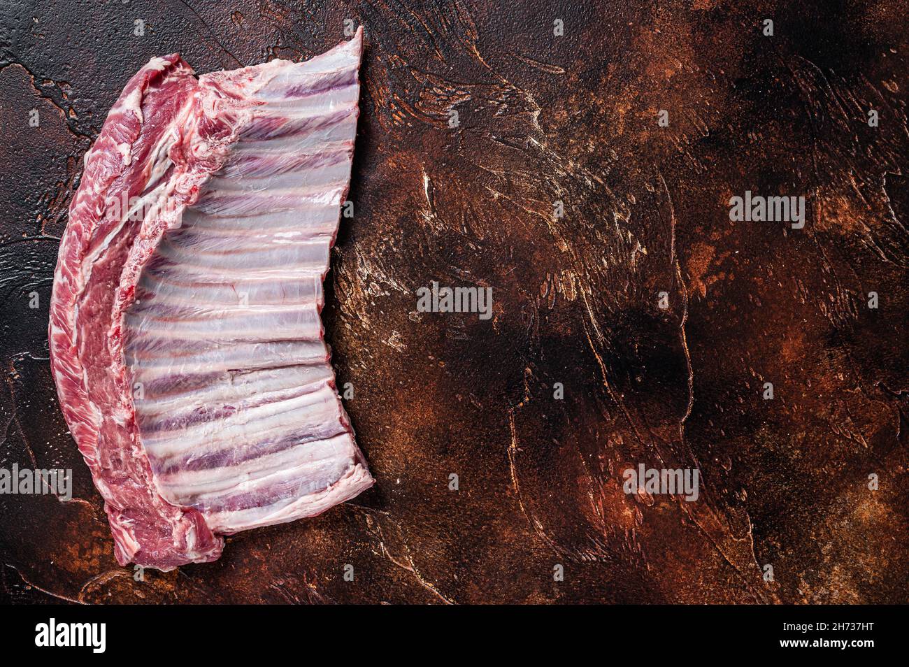 Raw rack of mutton lamb ribs on butcher board. Dark background. Top ...