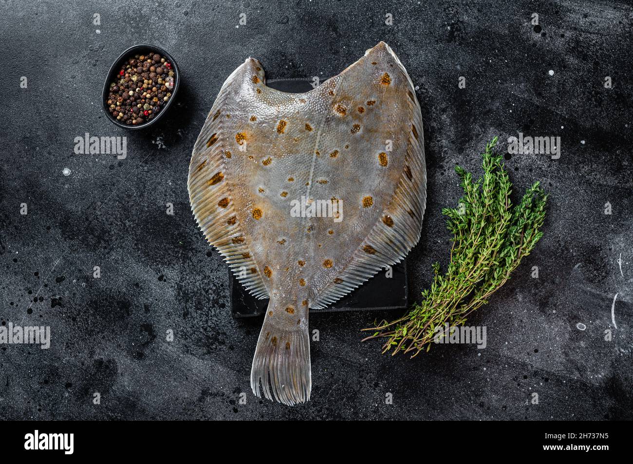Raw flounder flatfish fish on marble board with thyme. Black background ...