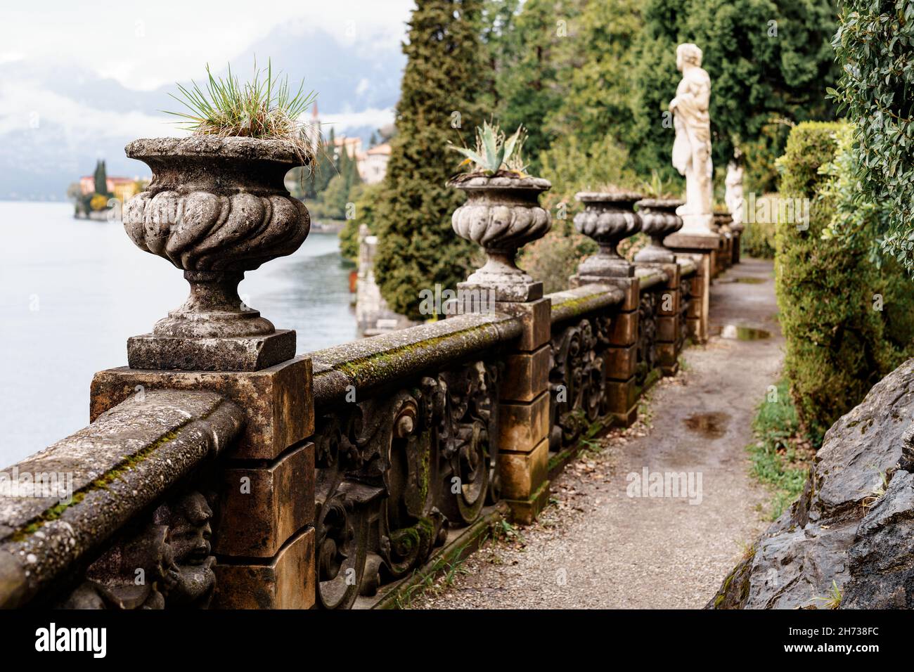 Stone balustrade with vases and statues on the shore. Villa Monastero ...
