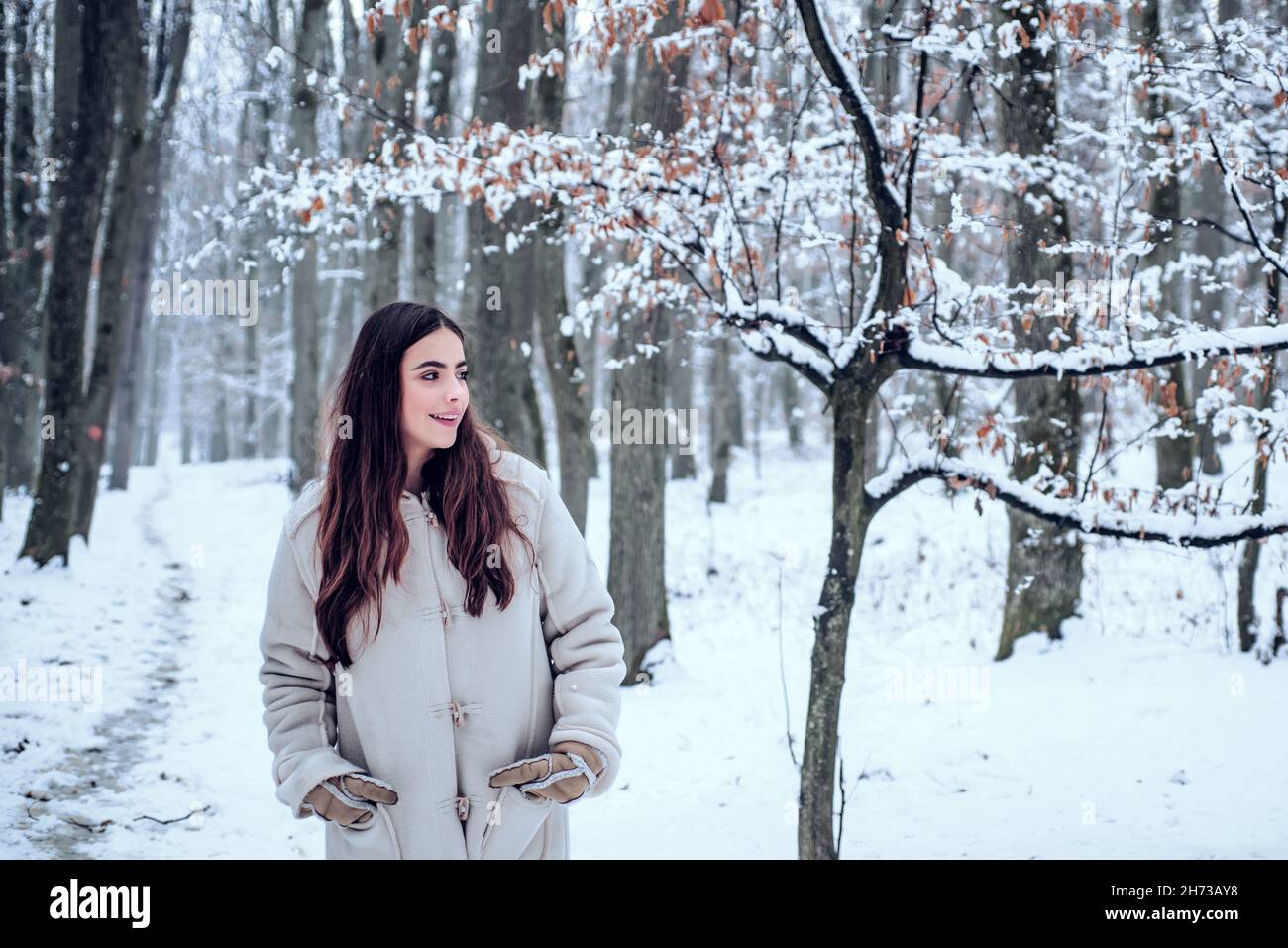 Winter woman. Portrait of a young woman in snow trying to warm herself ...