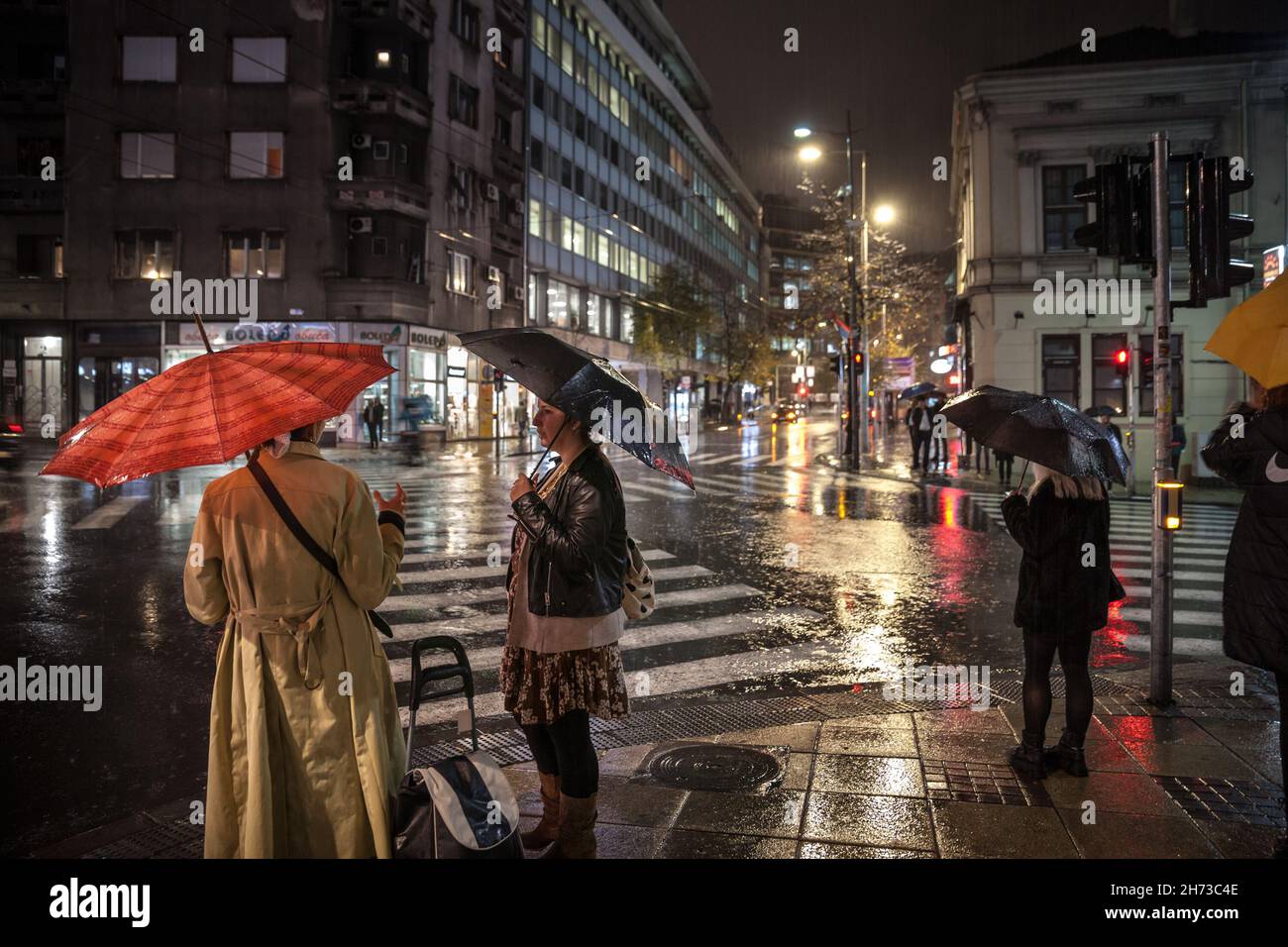 Picture of women with an umbrella waiting for green light to cross a ...