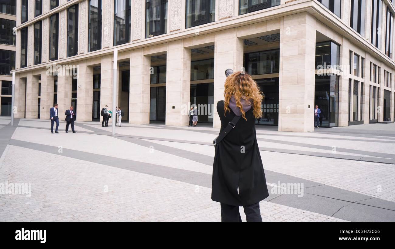 Woman takes photos with professional camera of business building ...