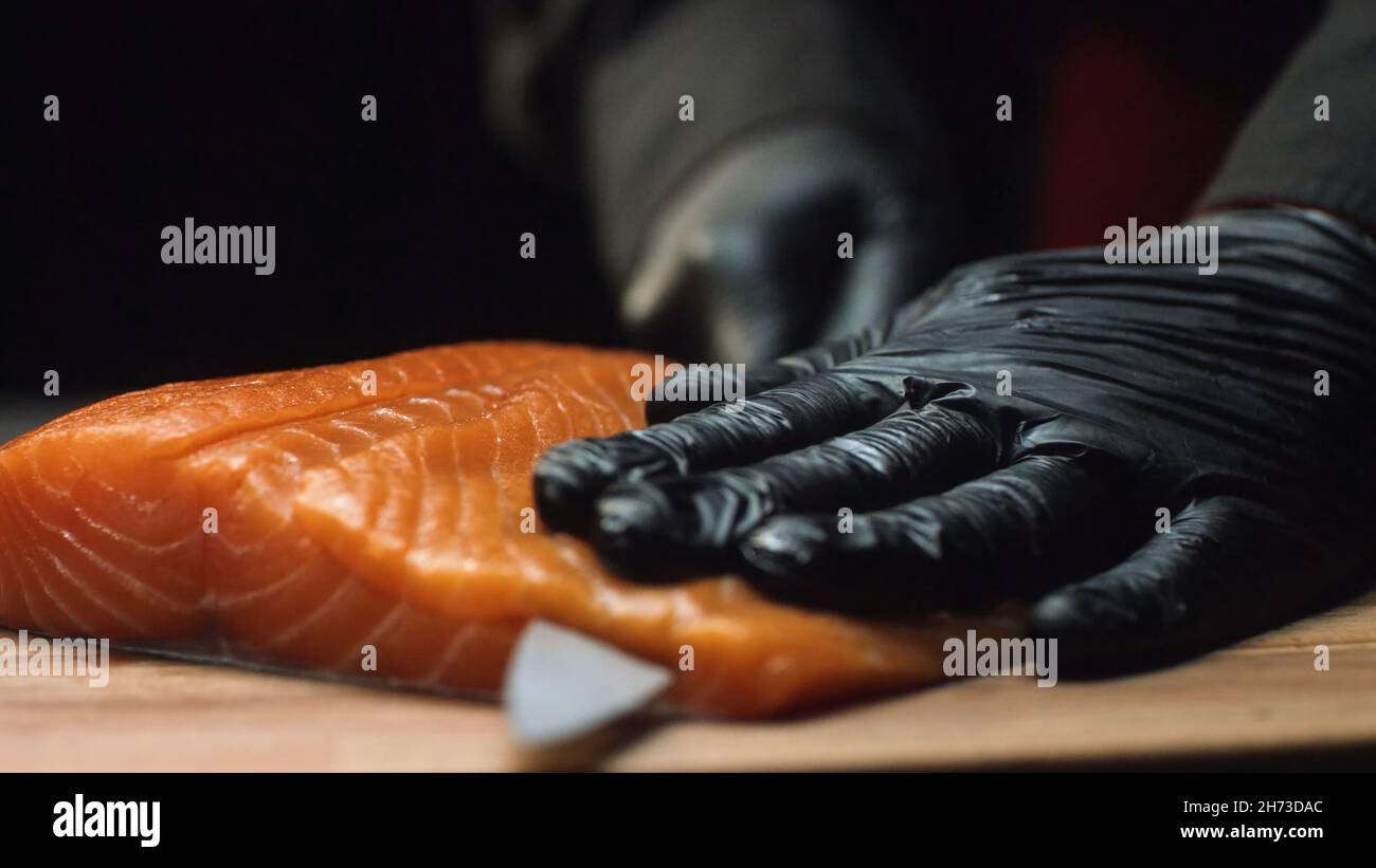 Close-up chef with piece of red salmon. Professional chef in black ...