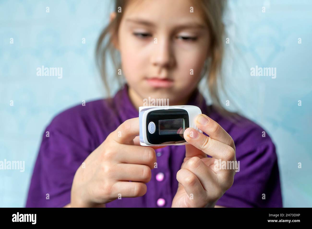 baby girl measures her blood oxygen saturation on a blue background ...