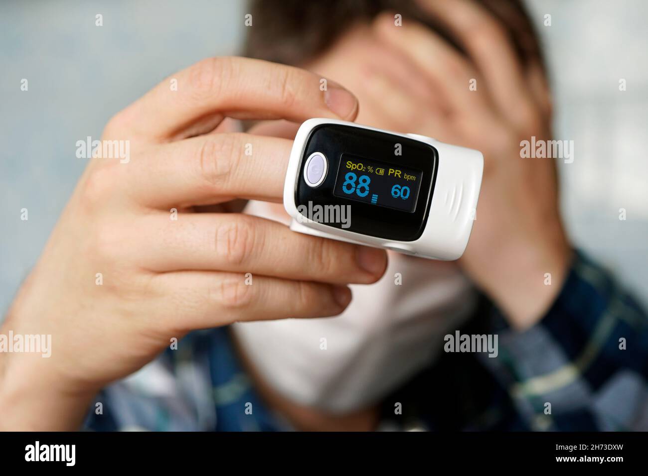 A patient in a medical mask measures blood saturation with an ...