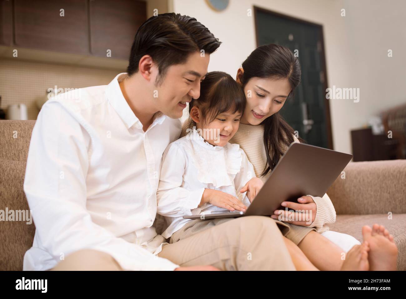 Happy and loving young family using a laptop at home Stock Photo - Alamy