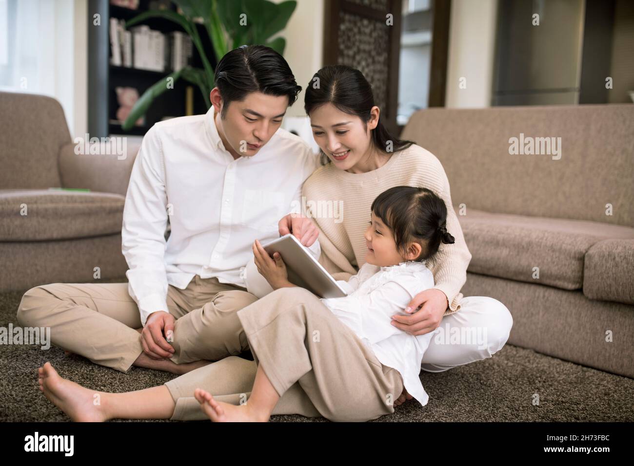 Happy young family using a digital tablet at home Stock Photo - Alamy