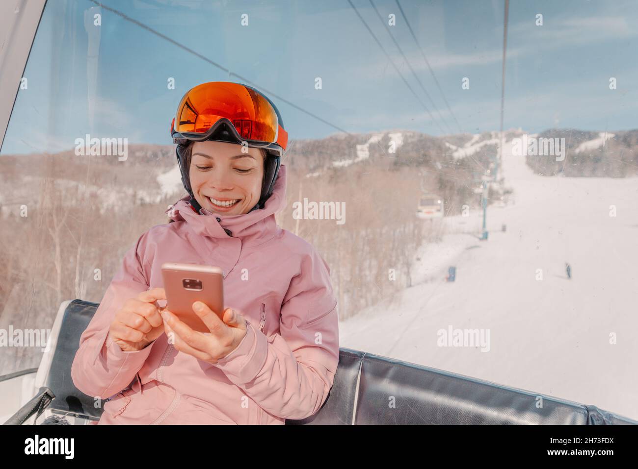 Ski holidays - Woman skier using phone app in gondola ski lift. Girl ...