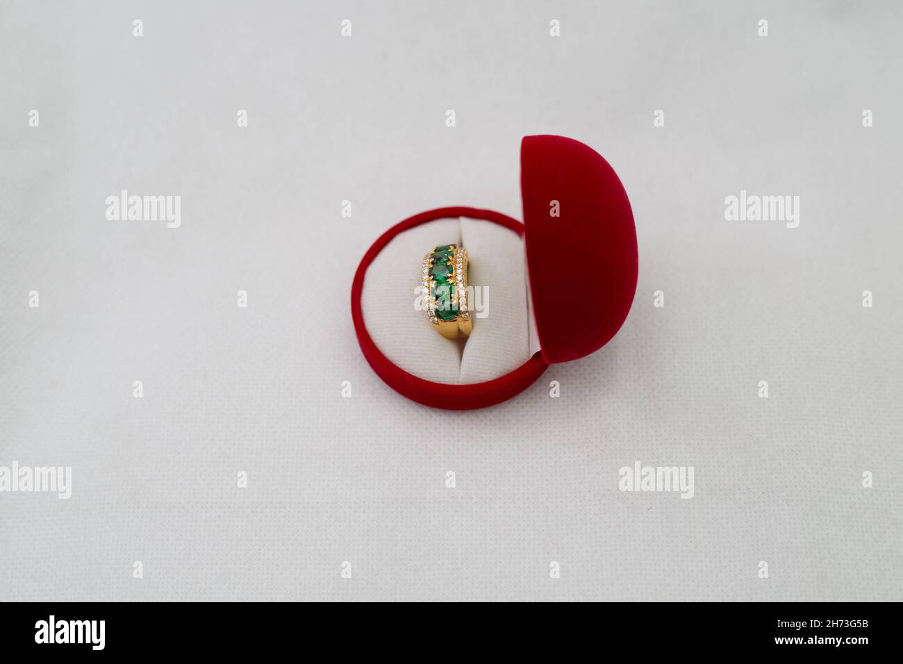 Luxurious gold ring with emeralds and diamonds in a red box on an ...