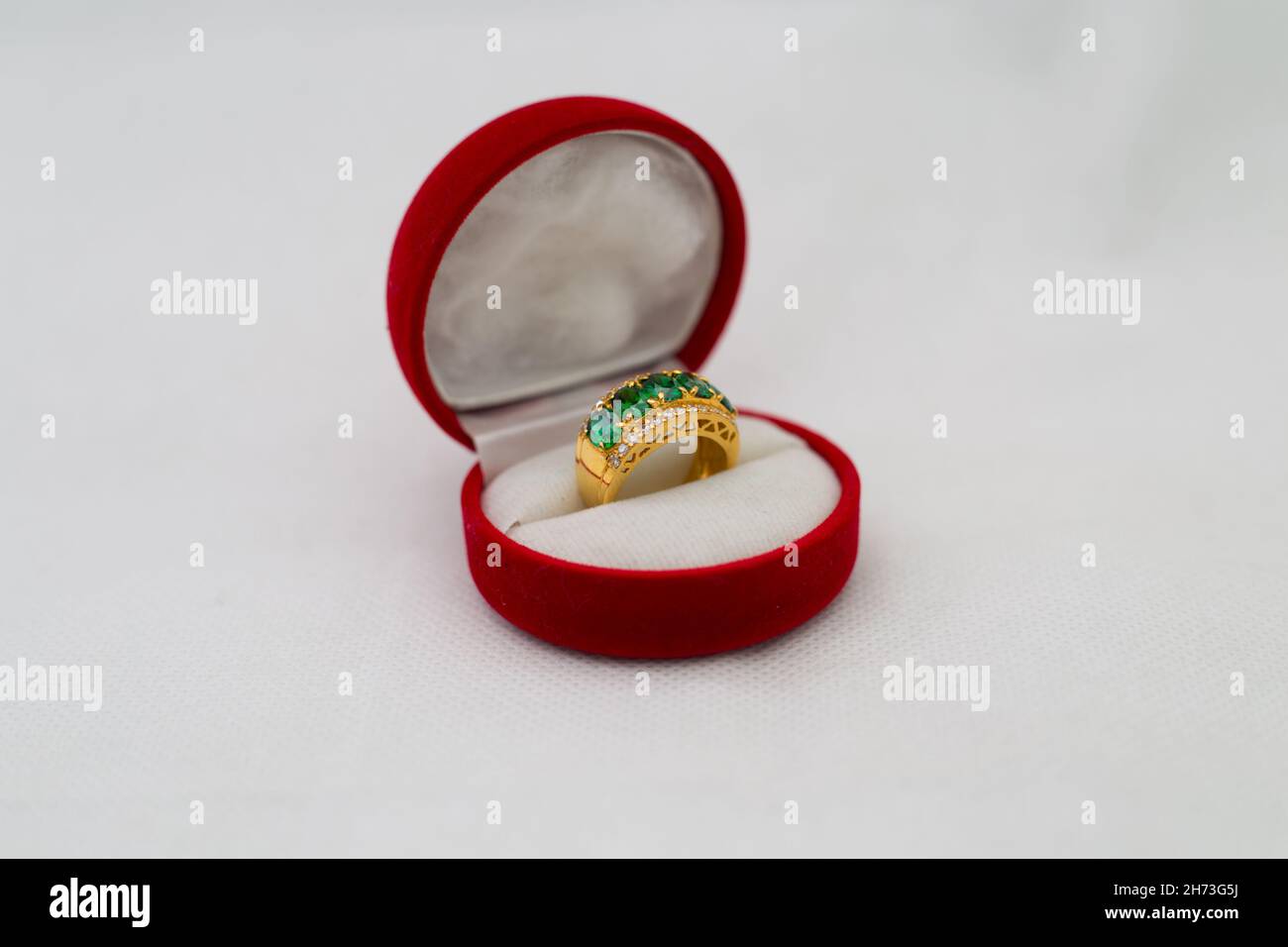 Closeup of a gorgeous gold ring with emeralds and diamonds in a red box ...