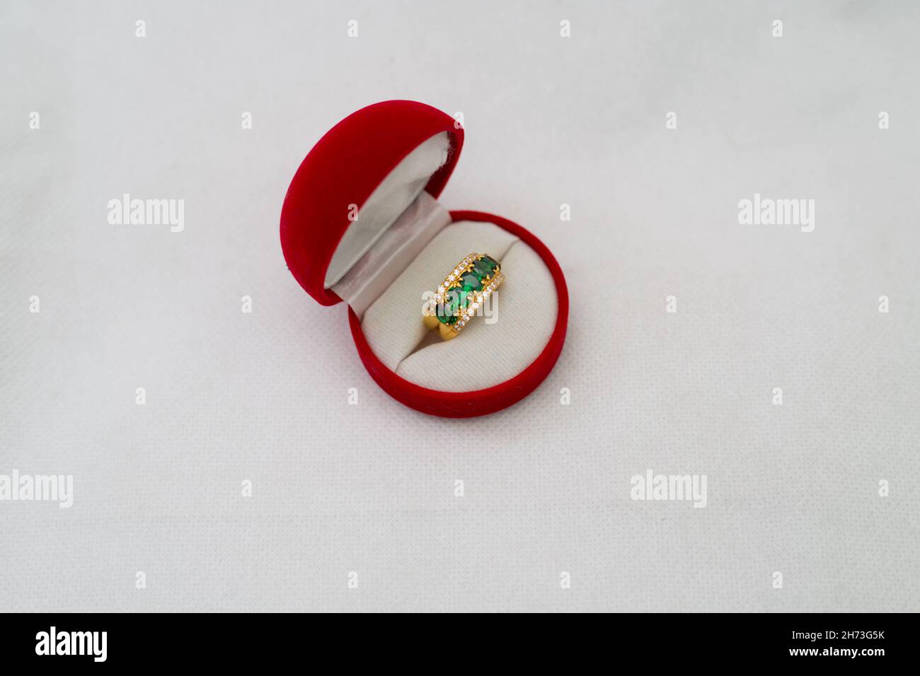 Gorgeous gold ring with emeralds and diamonds in a red box on a white ...