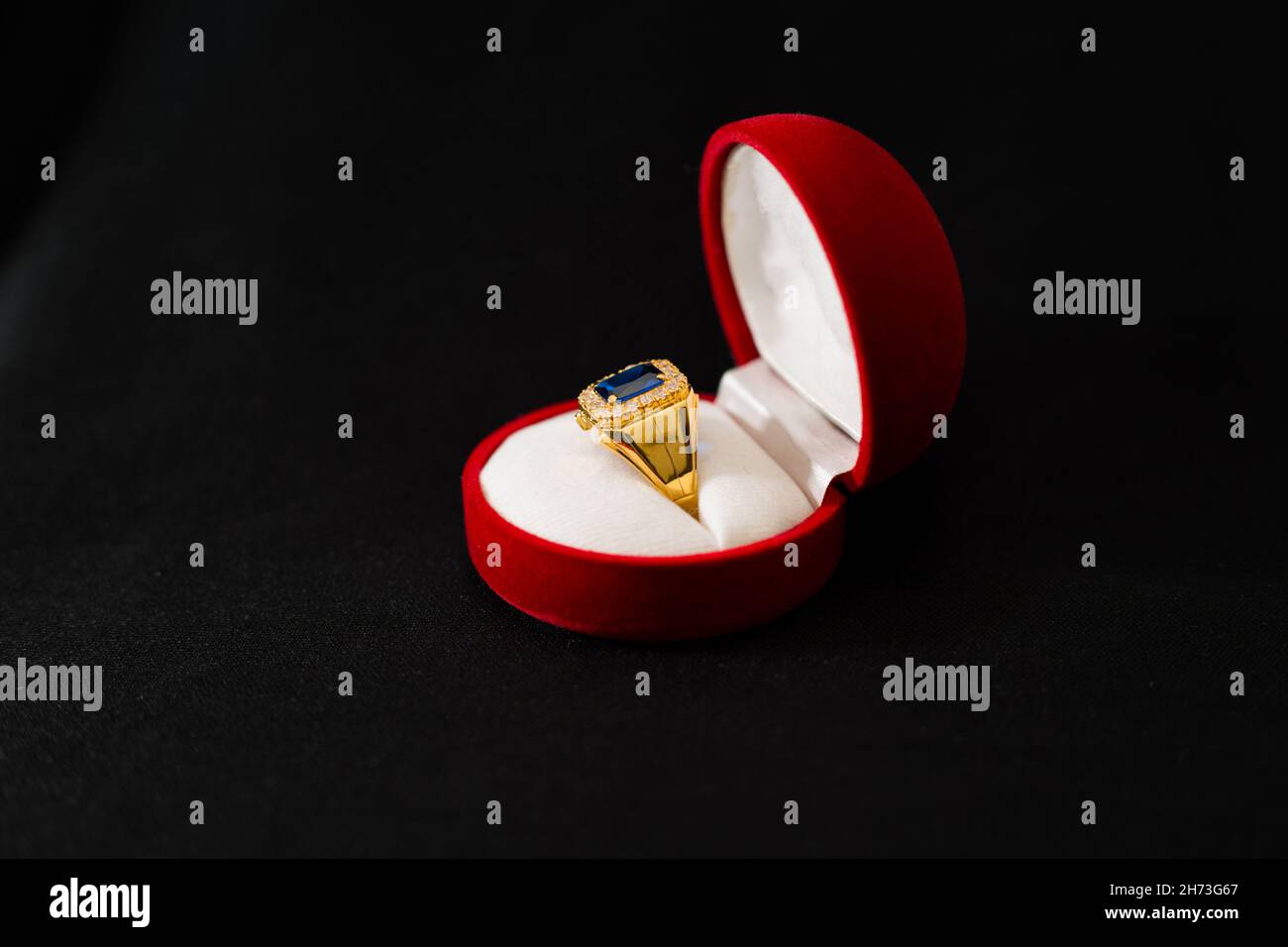 Gorgeous gold and sapphire ring in a red box on a black isolated ...