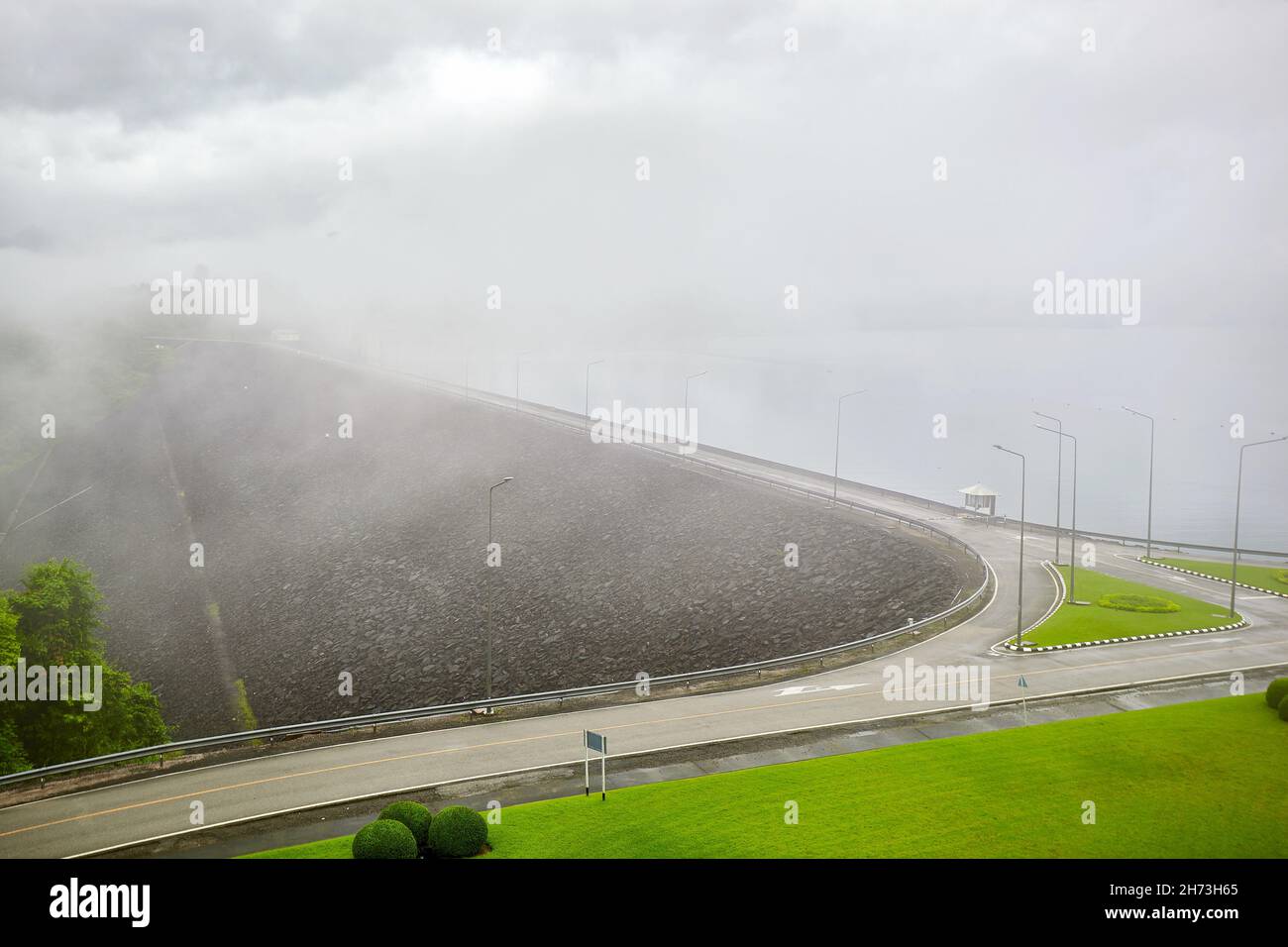 A beautiful scene of asphalt road with fog in the dam Stock Photo - Alamy