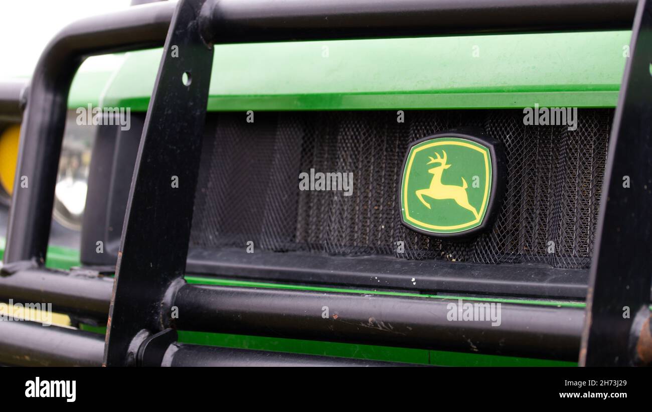 The John Deere emblem logo is seen on the front grille of a green, John ...