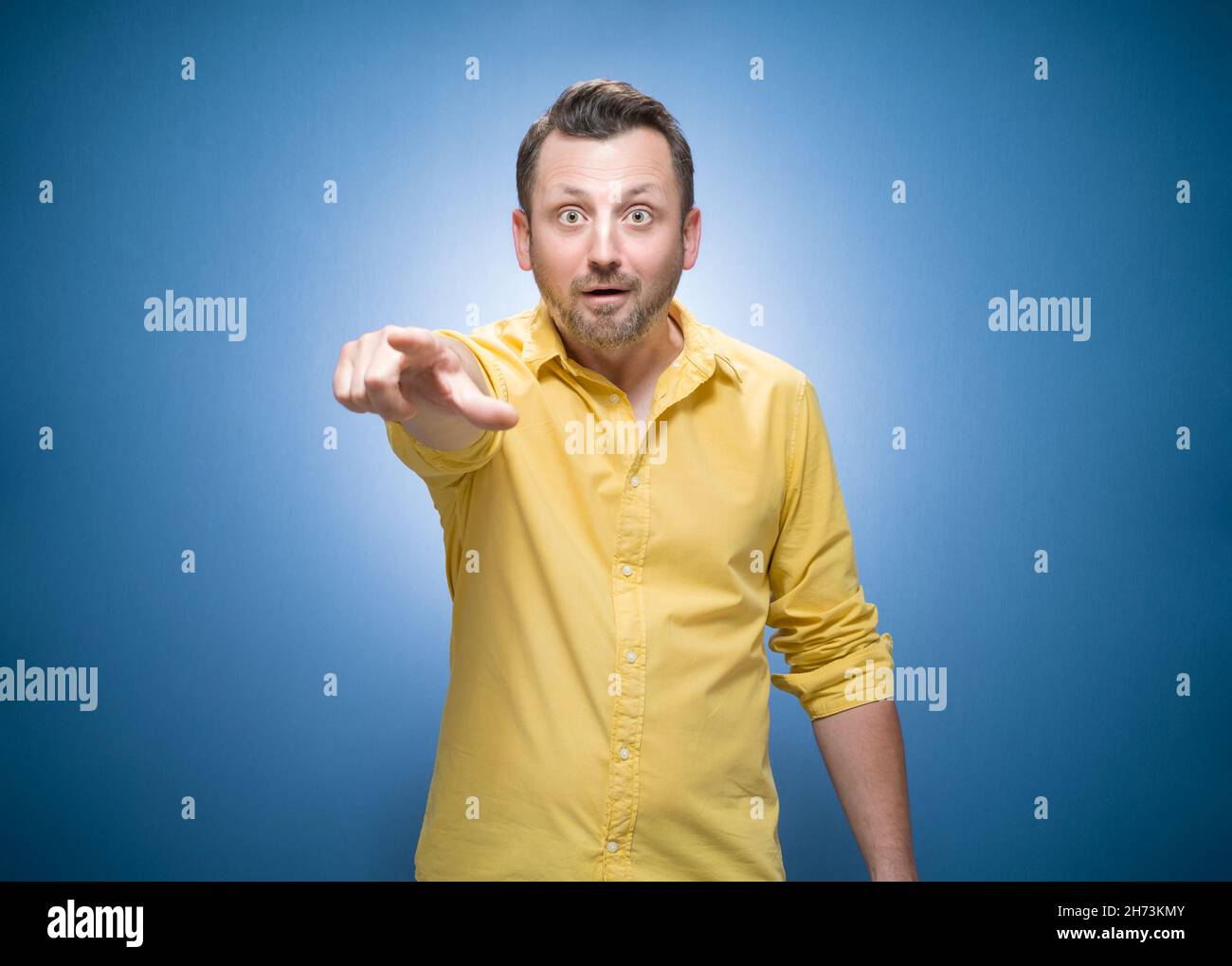 Funny scared man pointing or showing with finger to something over blue ...