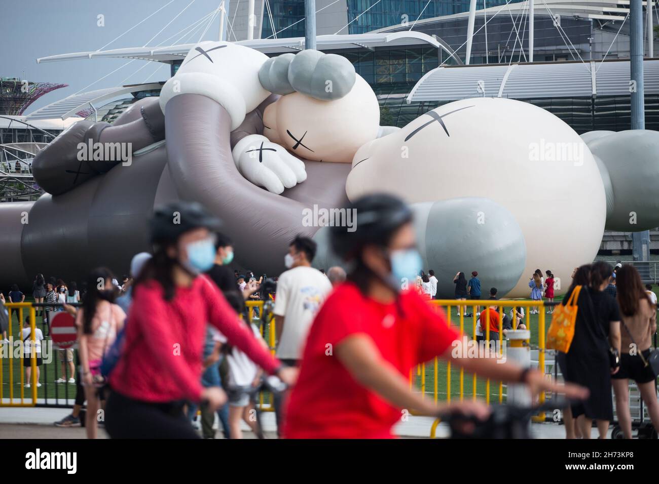 November 2021. Cyclists cycle past KAWS Holiday art installation ...