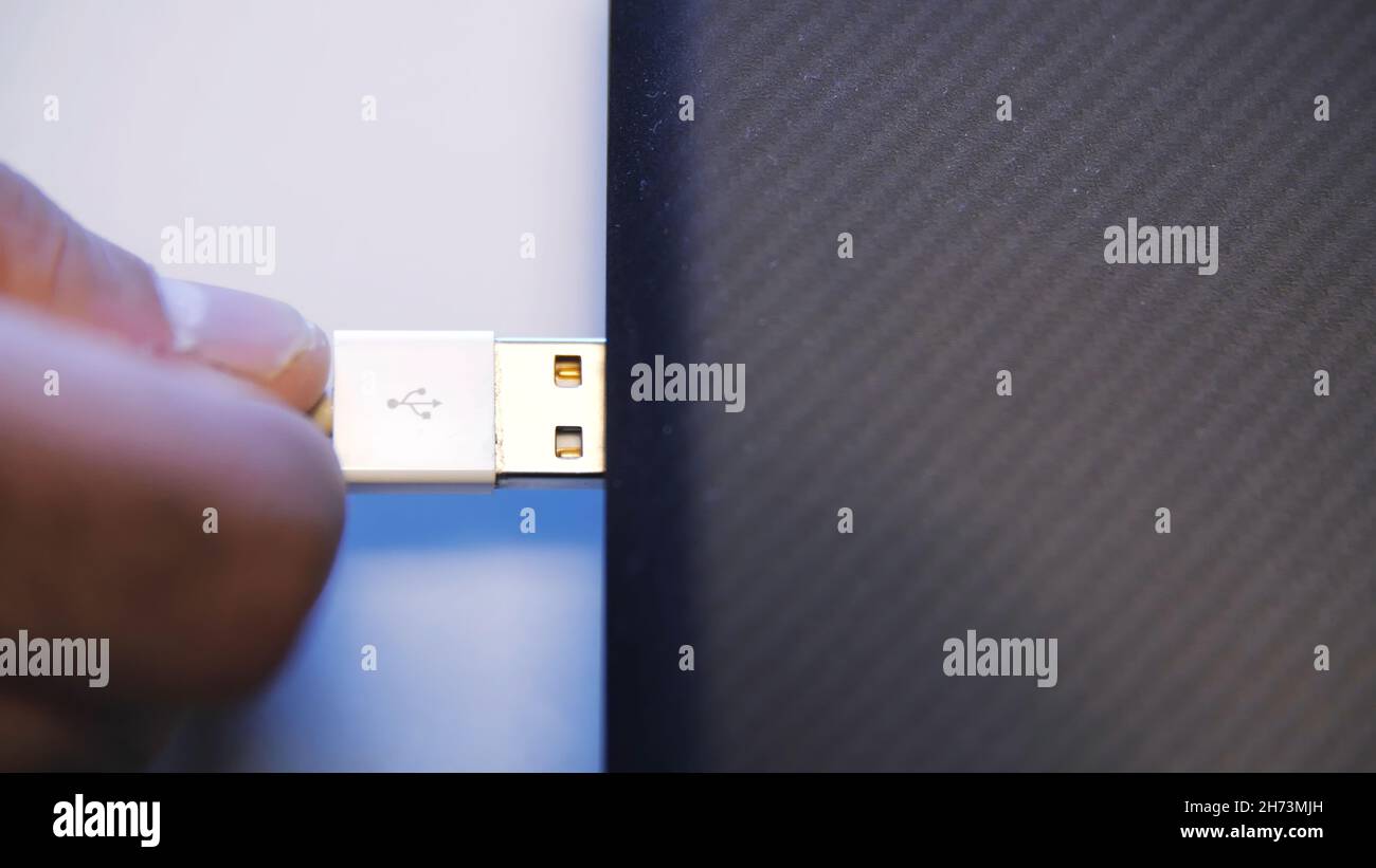 Close up of hand putting USB cable into external hard disk isolated on ...