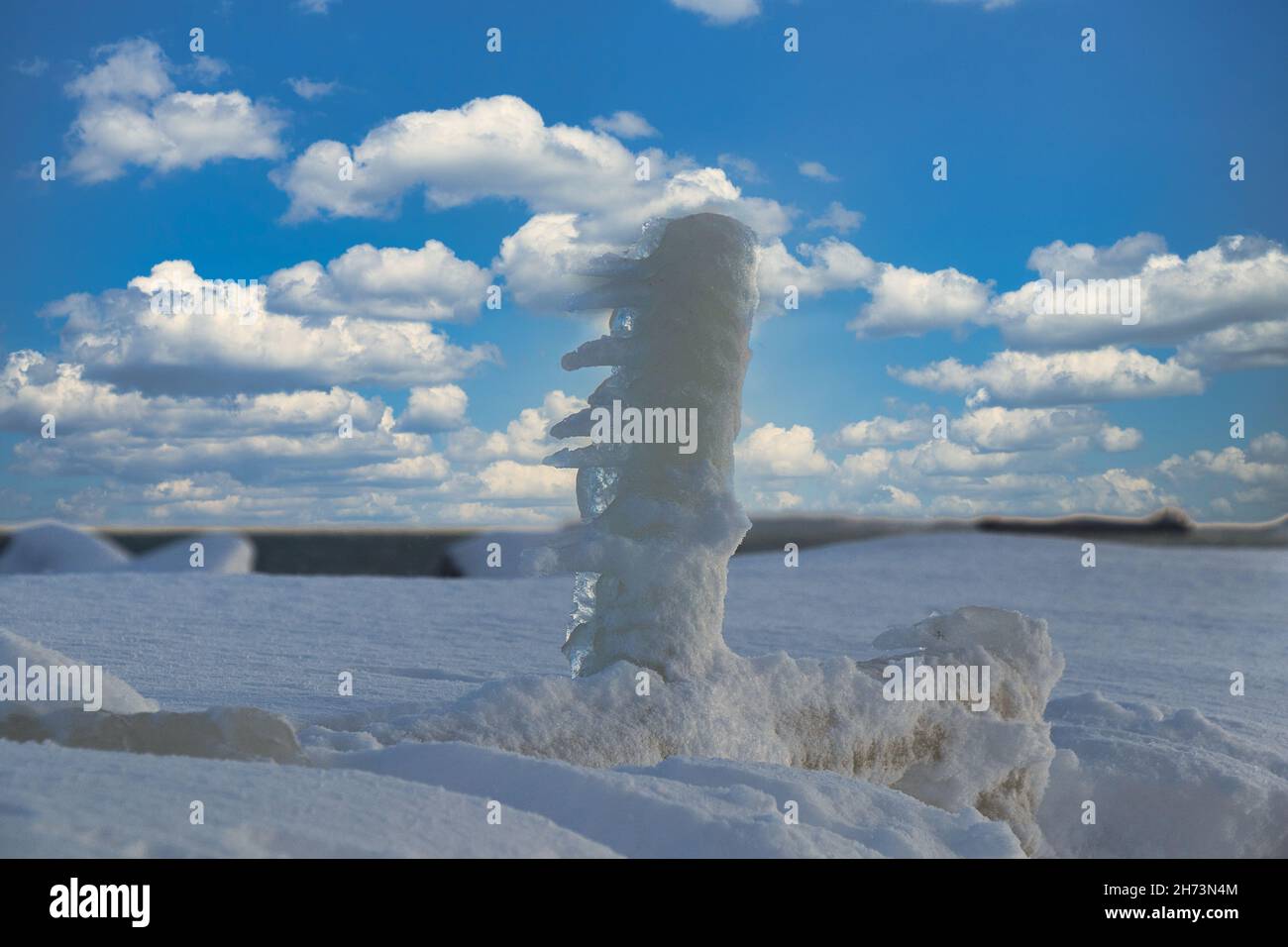 Landscape view of a big icicle, snow-capped and frozen beach and rocks ...