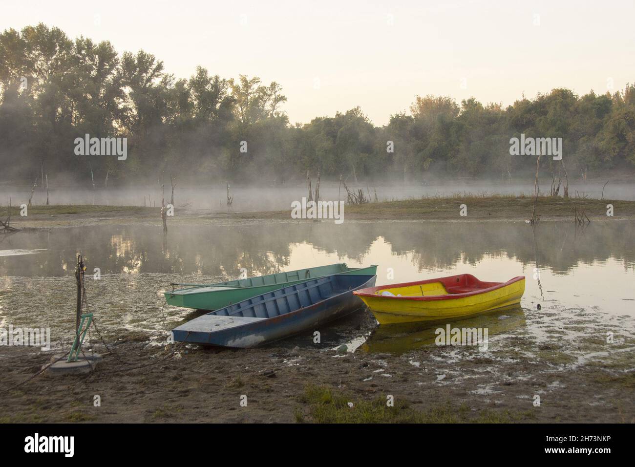 Boats on the riverbank with morning mist Stock Photo - Alamy