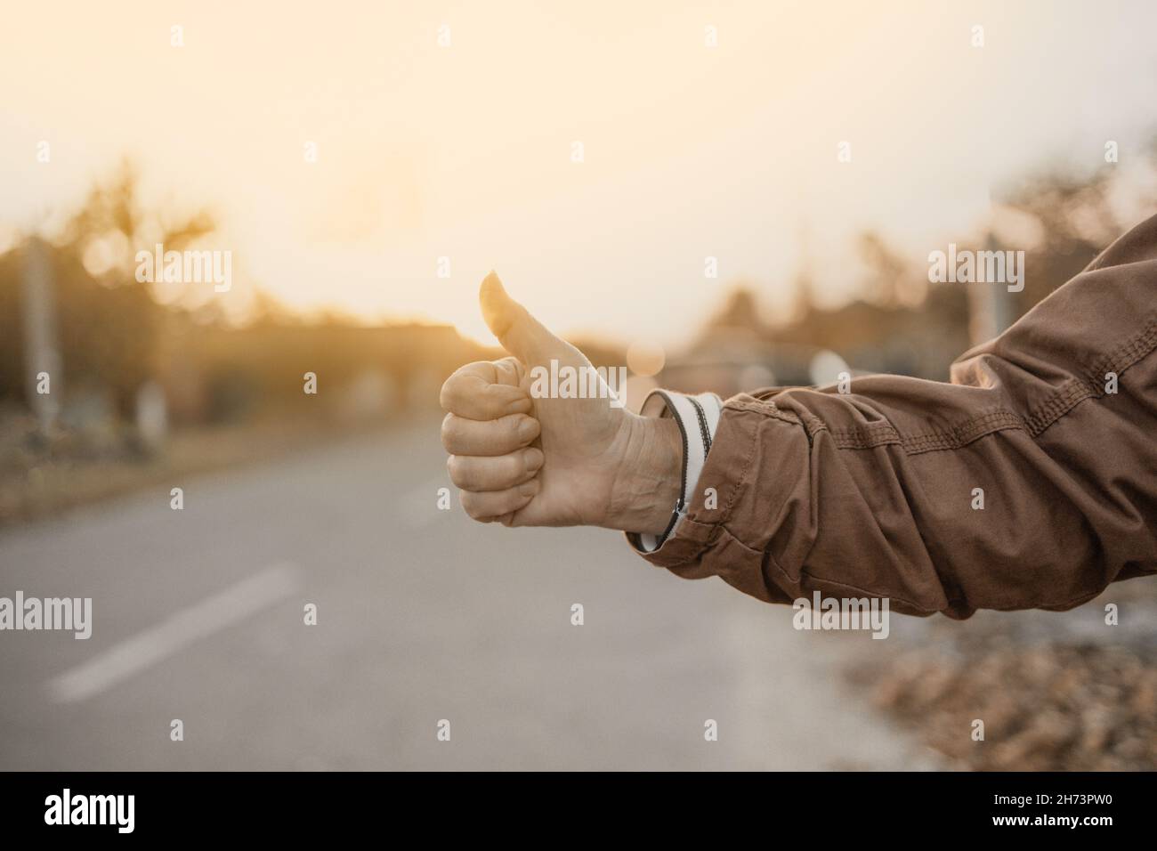Female hand and hitchhiking sign on road, traveling by autostop in the ...