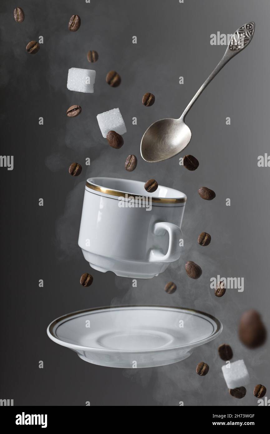 Falling coffee cup with a spoon, sugar pieces, and beans. Concept of ...