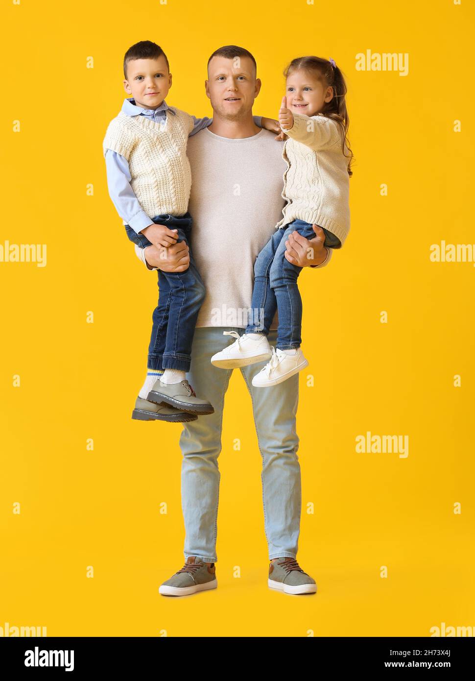 Portrait of father with little children on yellow background Stock ...