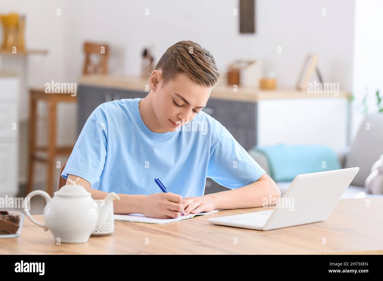 Teenage boy doing homework at table in kitchen Stock Photo - Alamy