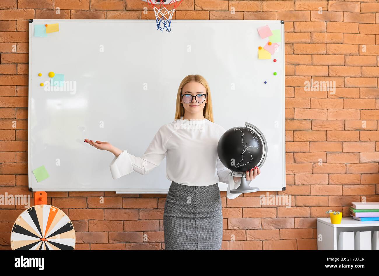 Young female teacher with globe conducting geography in classroom Stock ...