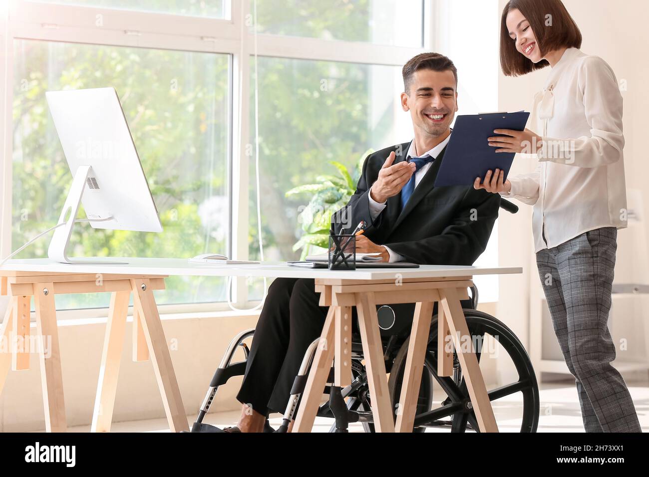 Young businessman with physical disability and his secretary in office ...