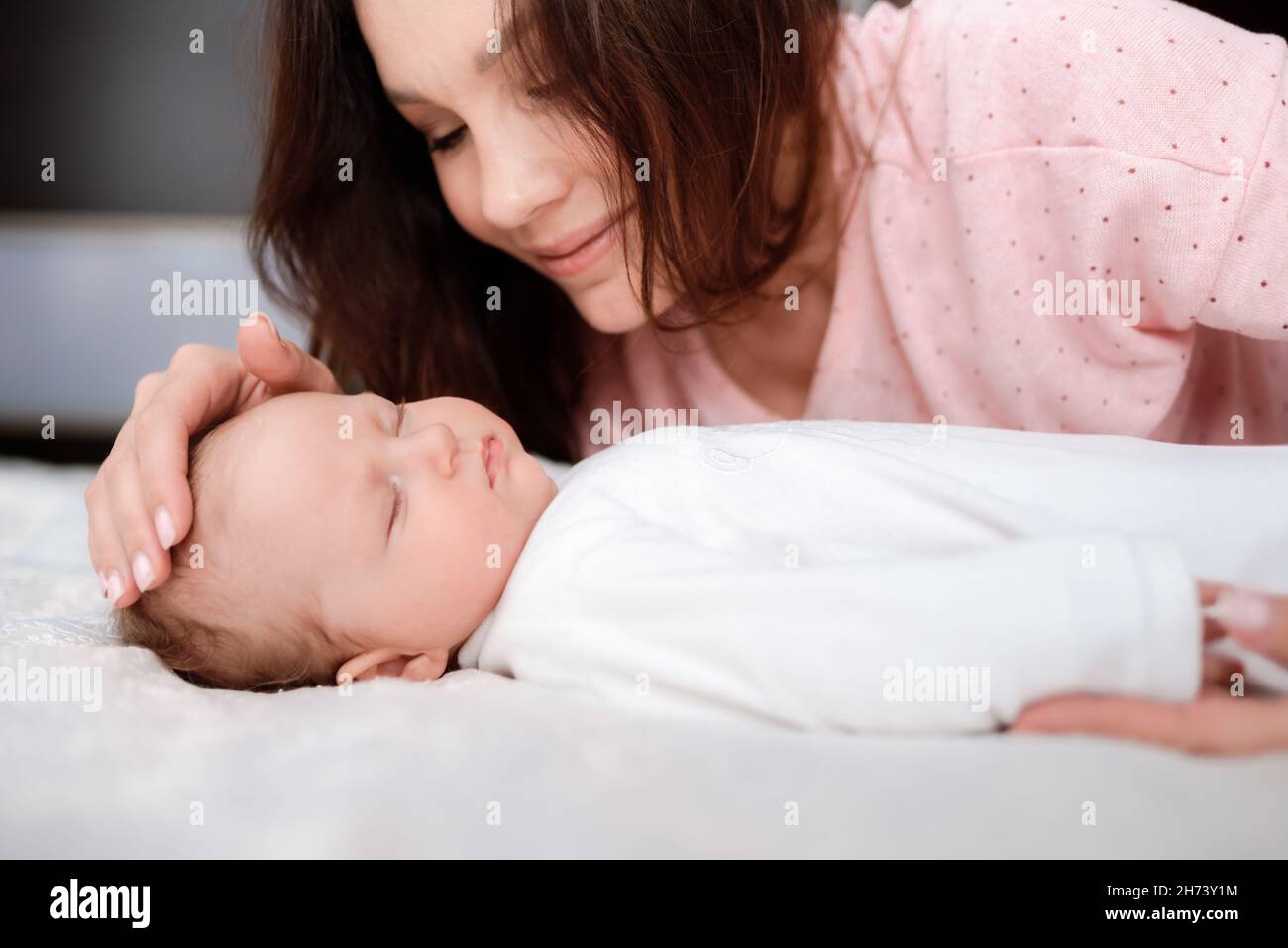 Young woman taking care of her baby in the bedroom Stock Photo - Alamy