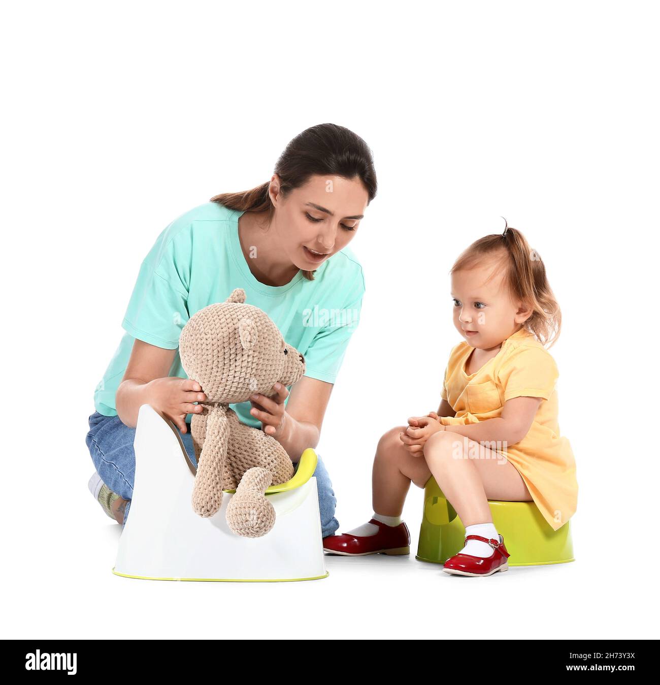 Mother potty training her little daughter on white background Stock ...