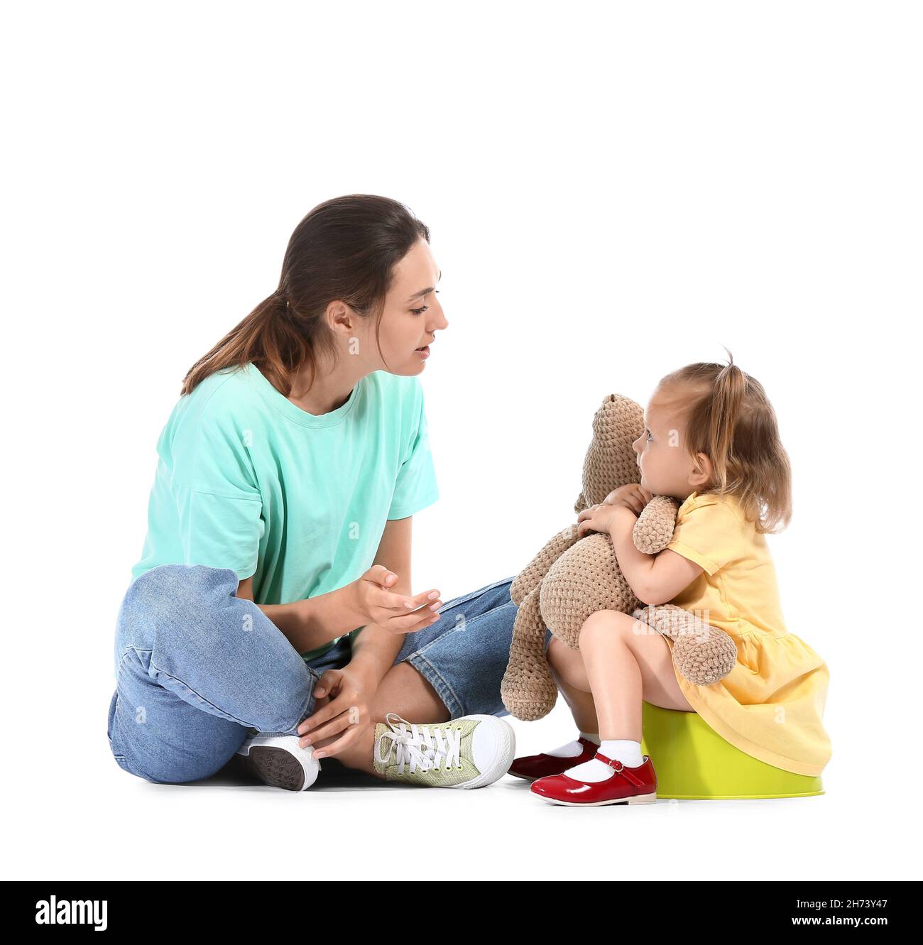 Mother potty training her little daughter on white background Stock ...