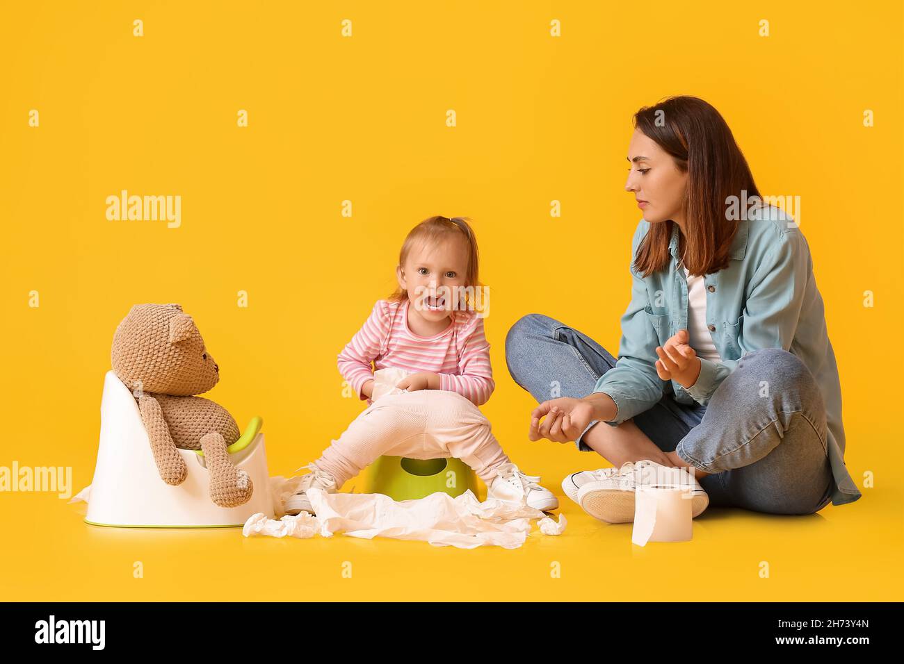 Mother potty training her little daughter on color background Stock ...