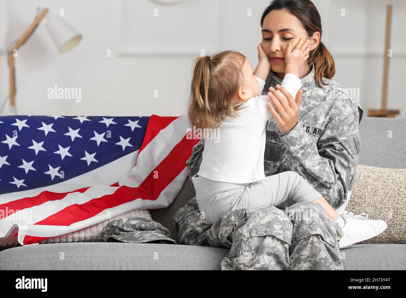 Female soldier of USA army with her little daughter sitting on sofa at home Stock Photo - Alamy