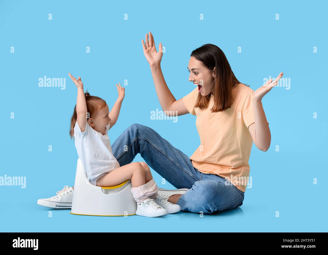Mother potty training her little daughter on color background Stock ...