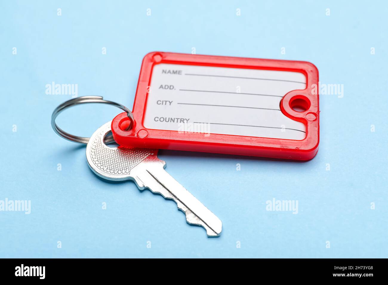 Key with red plastic tag on blue background Stock Photo - Alamy