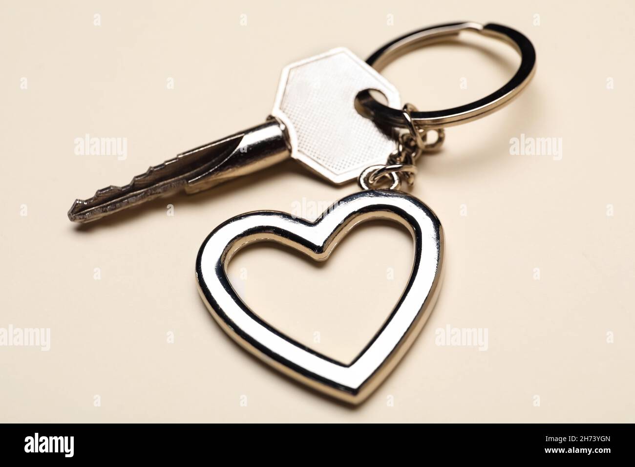 Key with heart shaped keychain on beige background, closeup Stock Photo ...